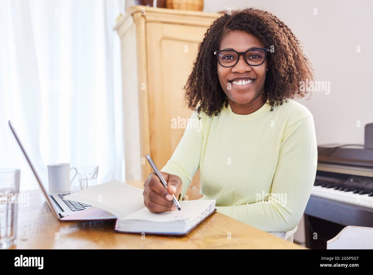 Happy African woman working as a freelancer in the home office while ...