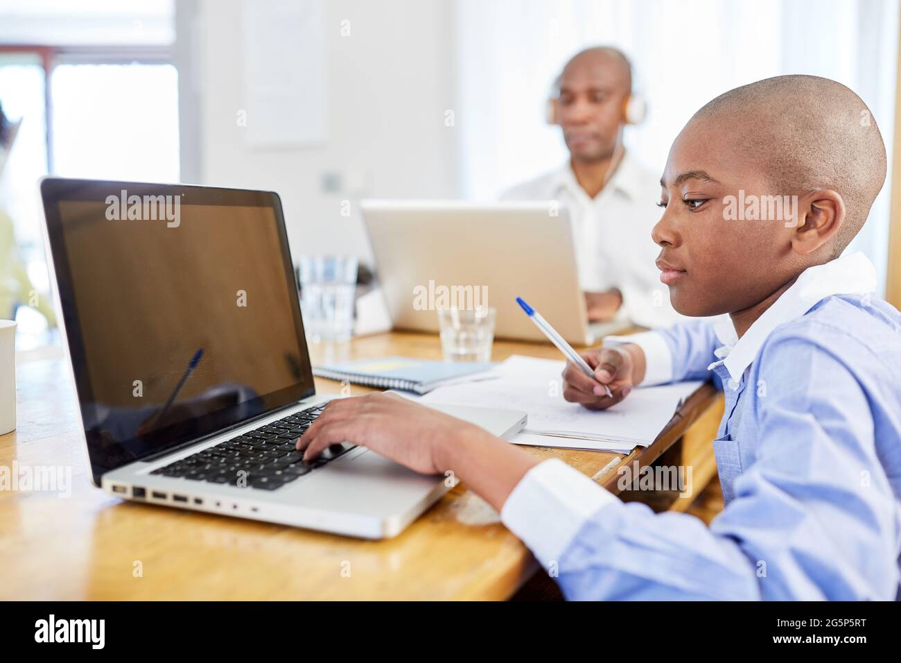 African boy as a student at laptop computer while homeschooling with ...
