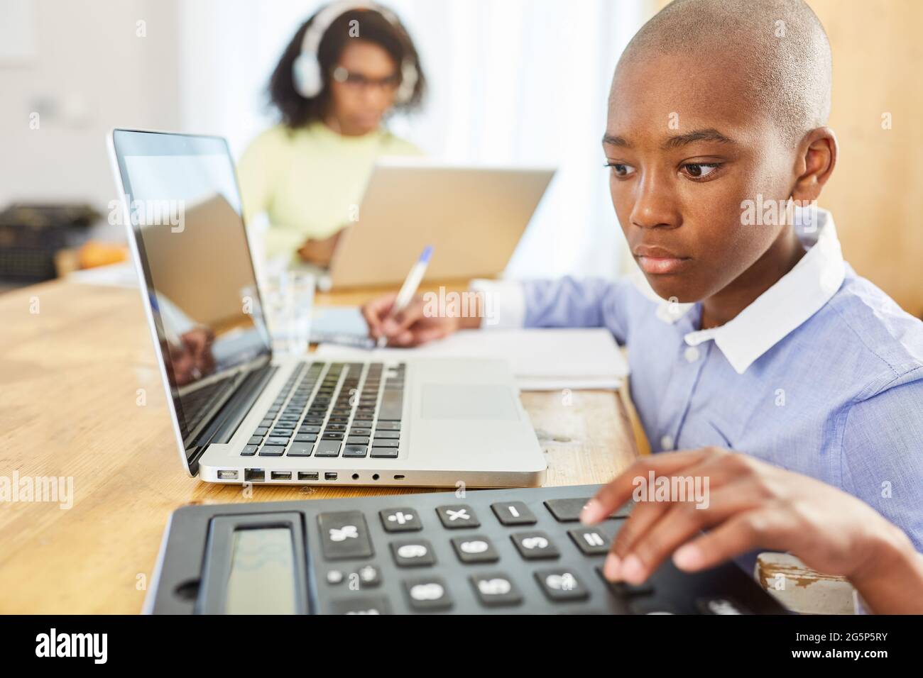 African boy using laptop computer while homeschooling at home with ...
