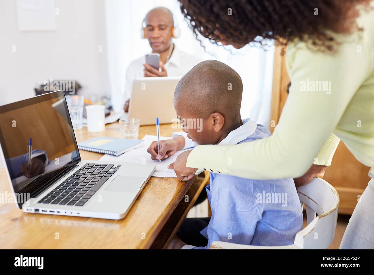 Mother helping son with distance learning on PC with father doing video ...