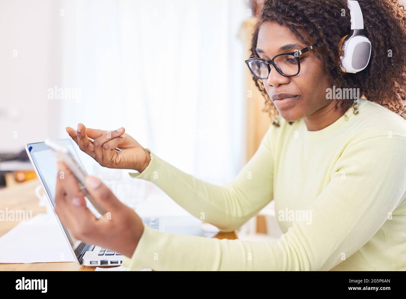 African American business woman using smartphone and headphones while ...
