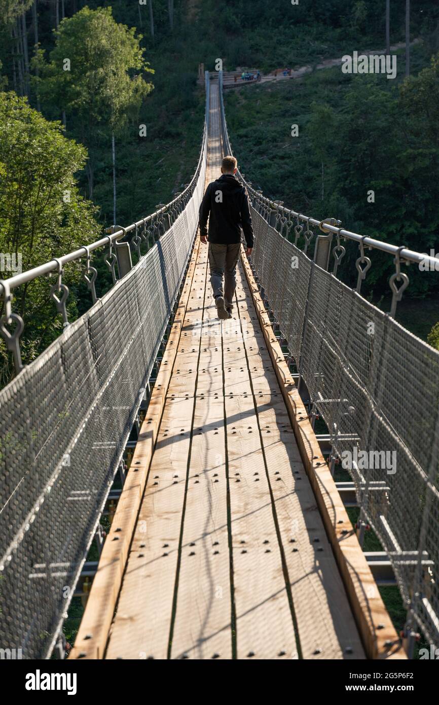 Man walking over a wooden suspension bridge Stock Photo - Alamy