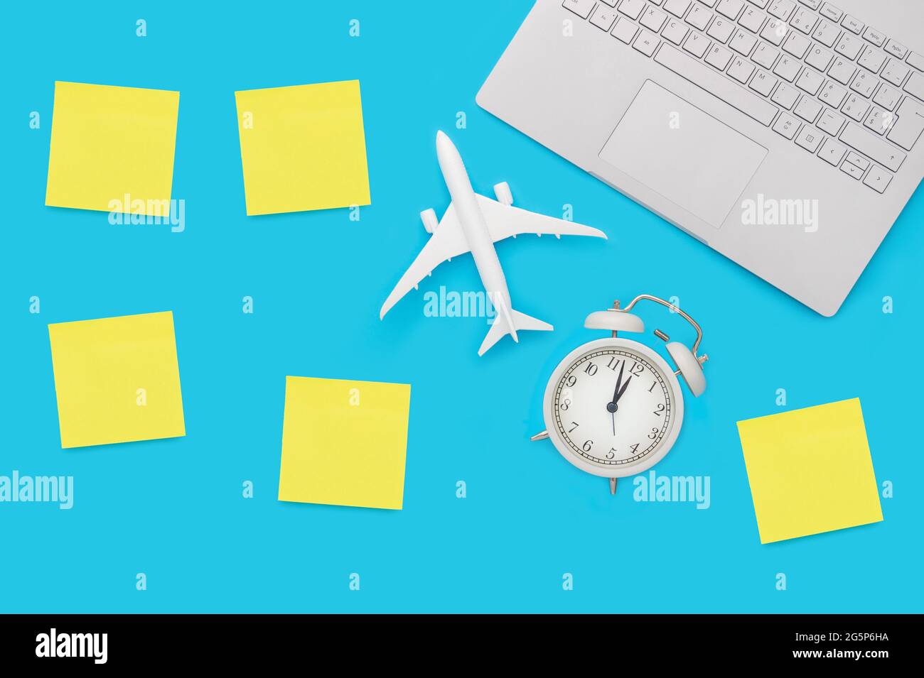 Top view of airplane figurine, alarm clock, sticky notes and a computer ...