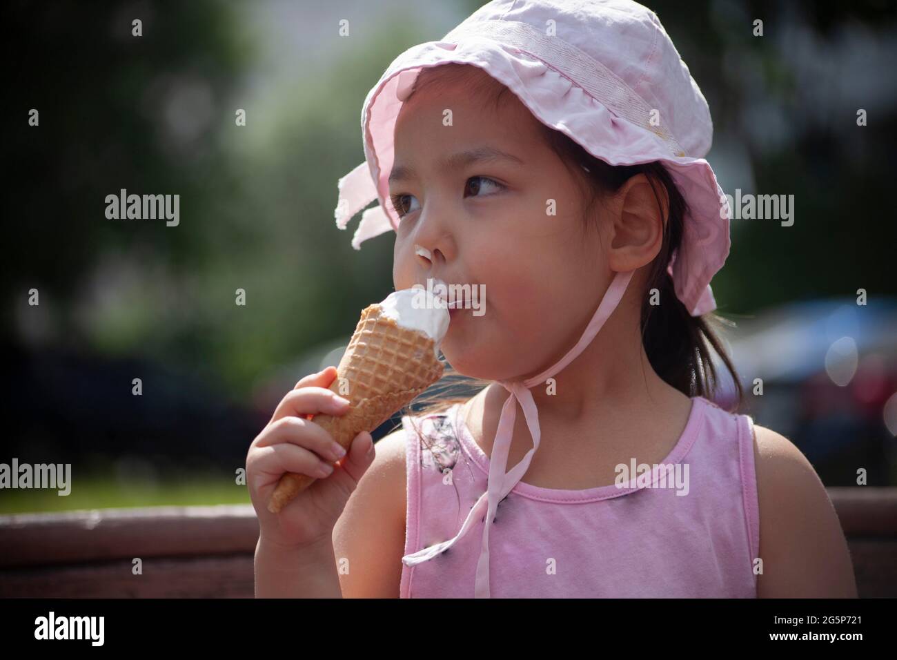 A child eats ice cream. The girl bites the sweetness. Summer ice cream ...