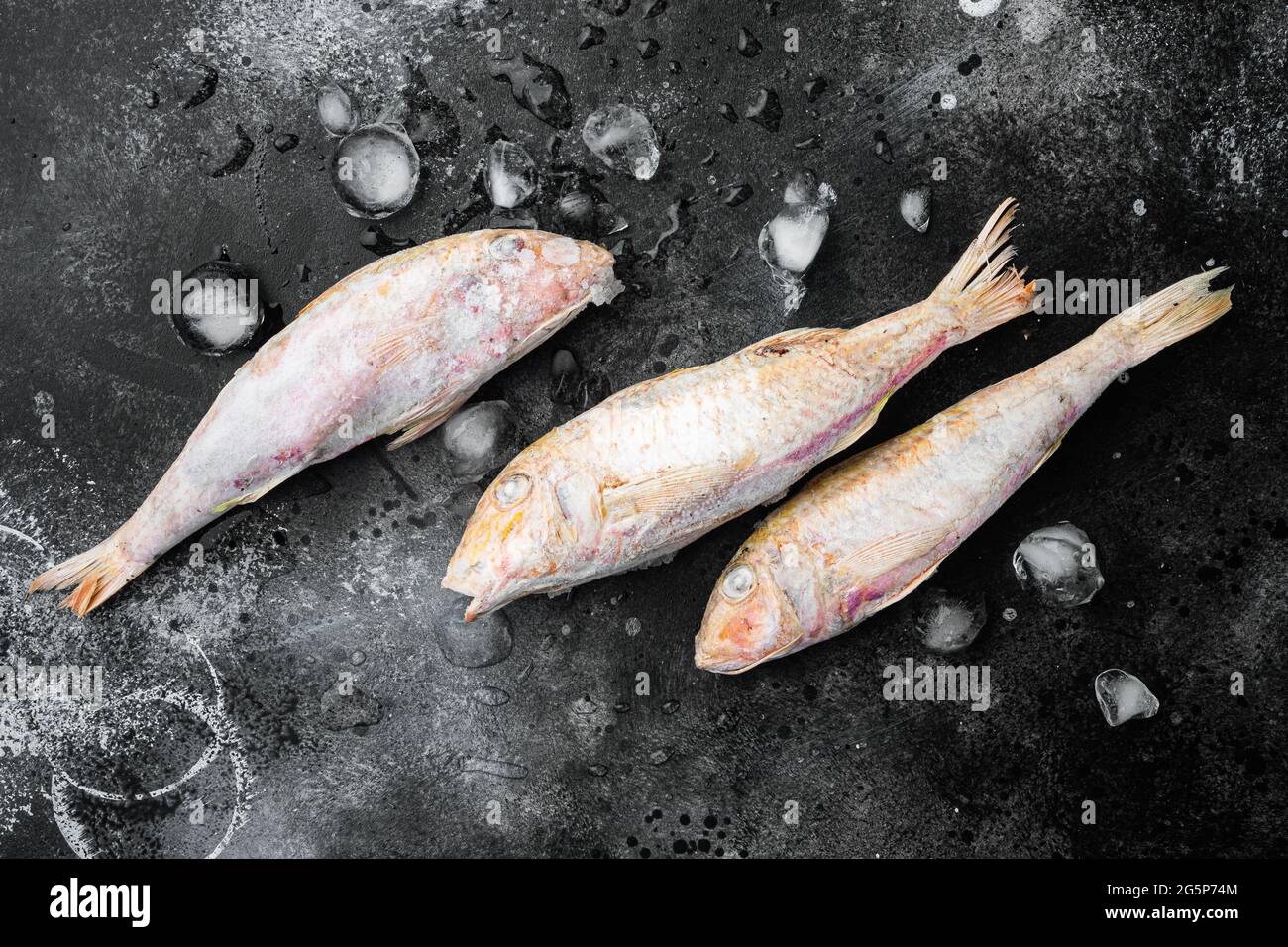 Frozen surmullet fish set, on black dark stone table background, top ...
