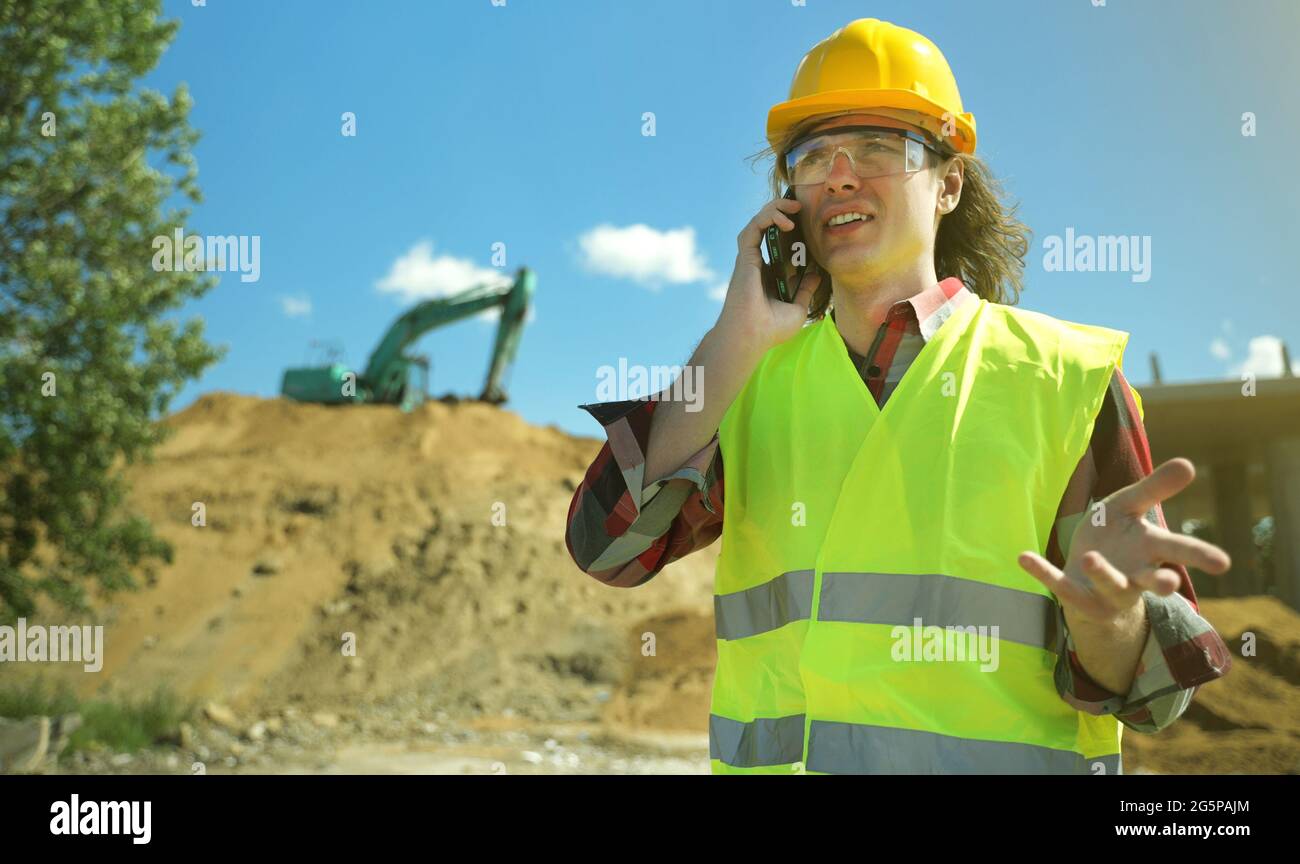 Builder talking by smartphone at construction site Stock Photo - Alamy