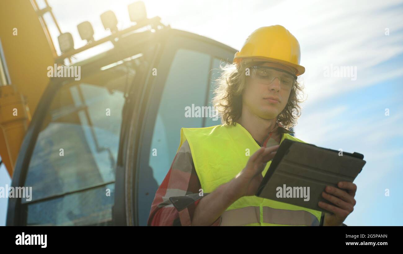 Excavator operator in hard hat using tablet pc Stock Photo - Alamy