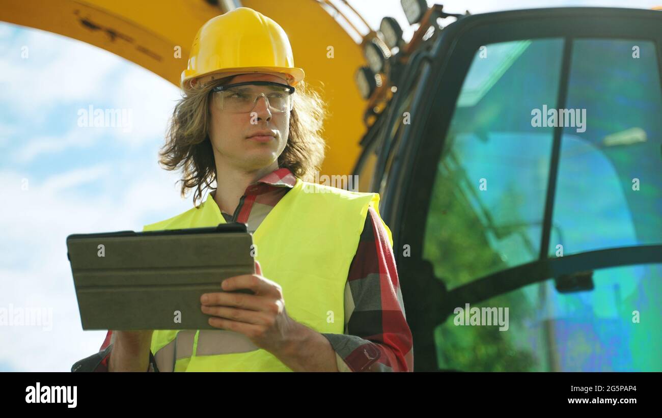 Excavator operator in hard hat using tablet pc Stock Photo - Alamy