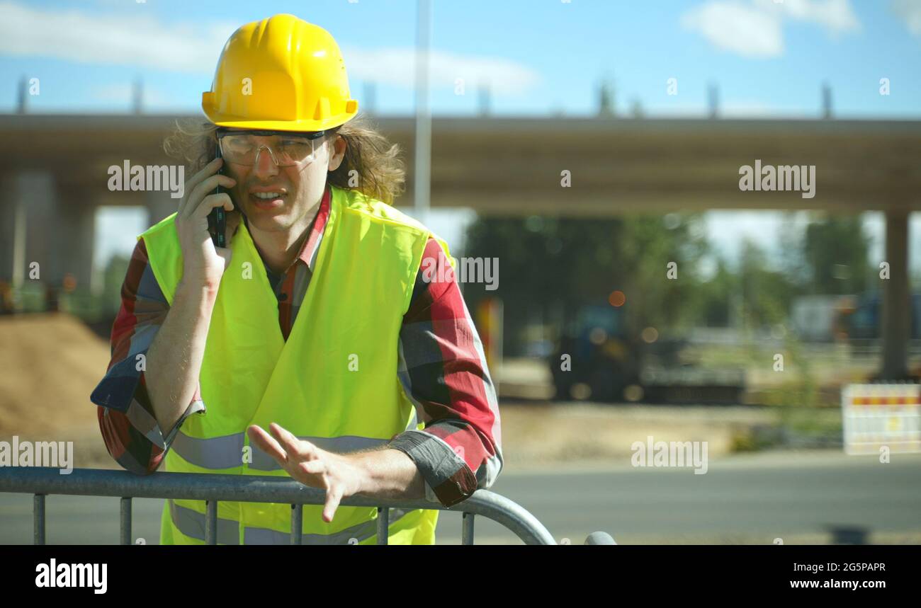 Builder talking by smartphone at construction site Stock Photo - Alamy