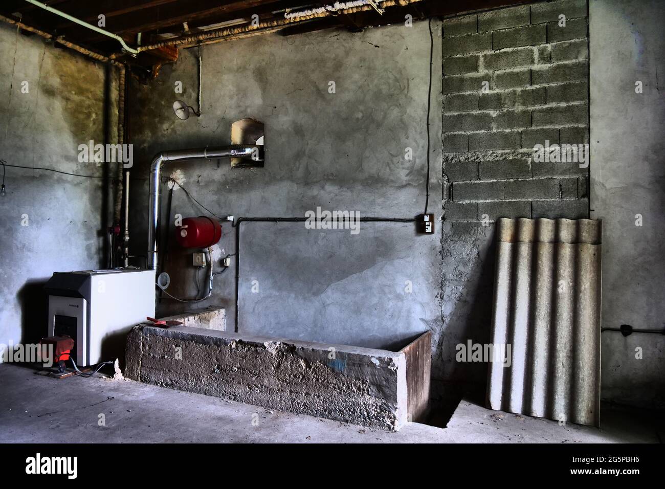 Disused boiler in a wide empty basement of an old abandoned house ...