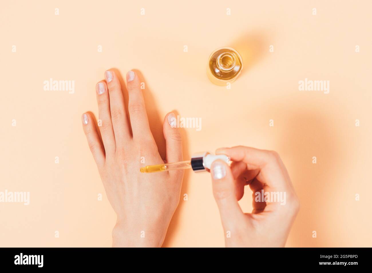 Female hands apply cosmetic oil from pipette to skin next to open ...