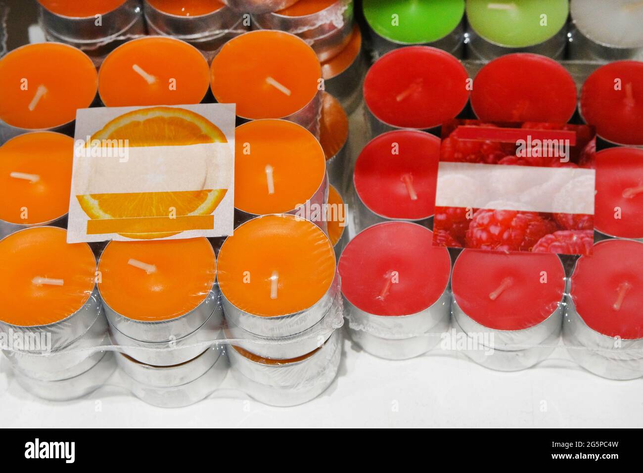 Paraffin candles lying on shelf in shop. Variety yellow and red aroma ...