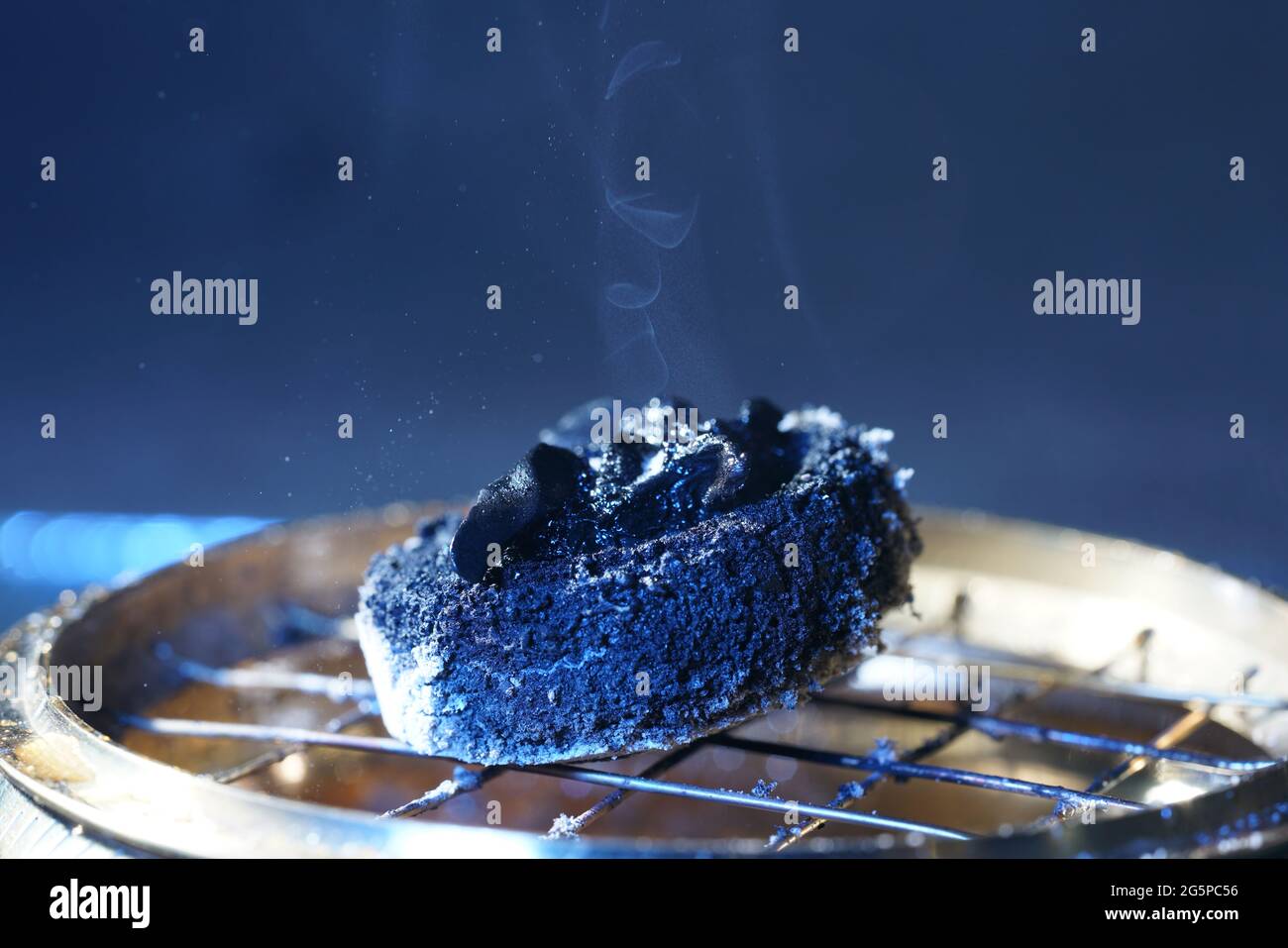 Closeup round-shaped coal burning with dark background Stock Photo - Alamy