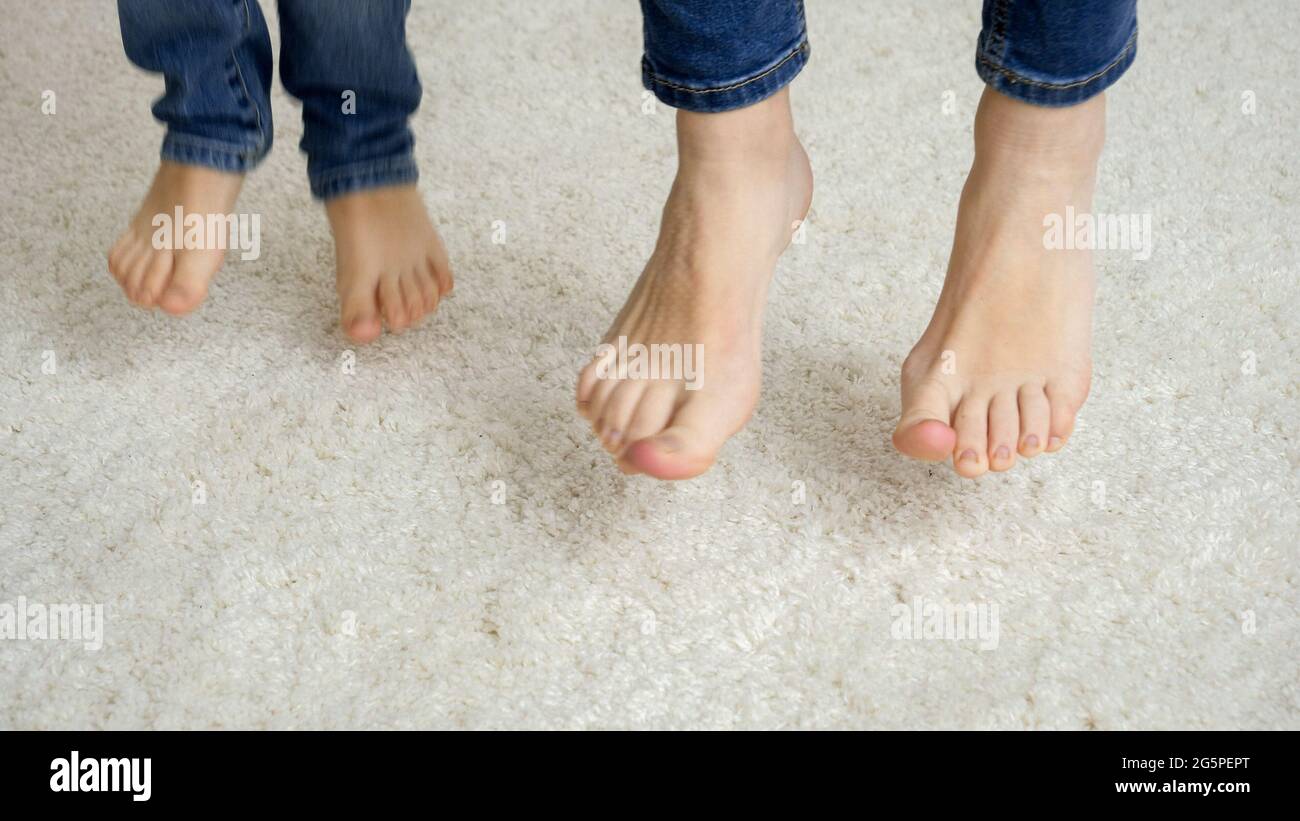 Closeup of mother and child feet jumping on soft carpet Stock Photo - Alamy