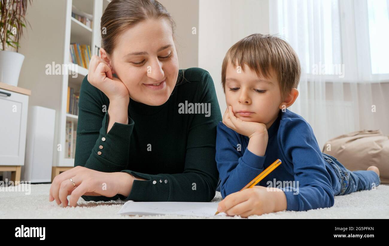 Little boy and young mother lying on floor in living room and doing ...