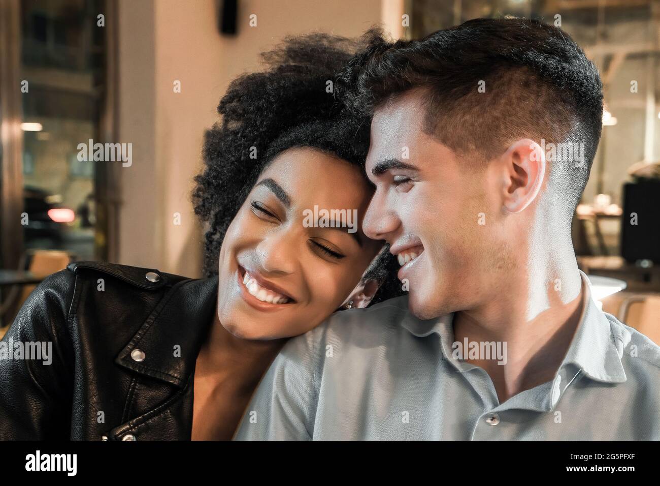 Multiracial couple of young lovers joining heads together in a tender ...