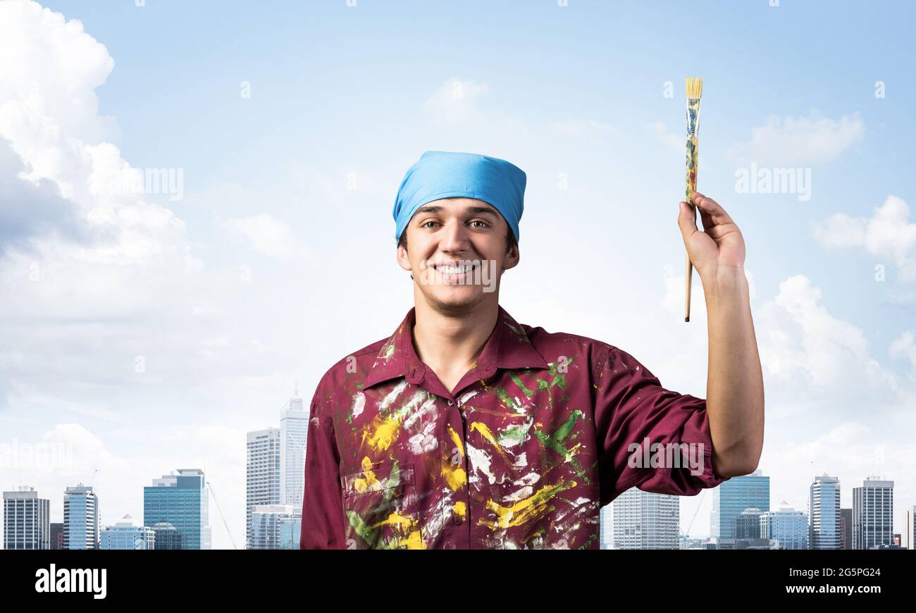 Smiling young painter artist pointing upwards Stock Photo - Alamy
