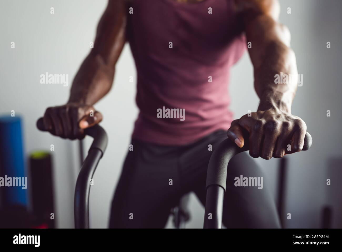 Midsection of african american man exercising at gym using rowing ...