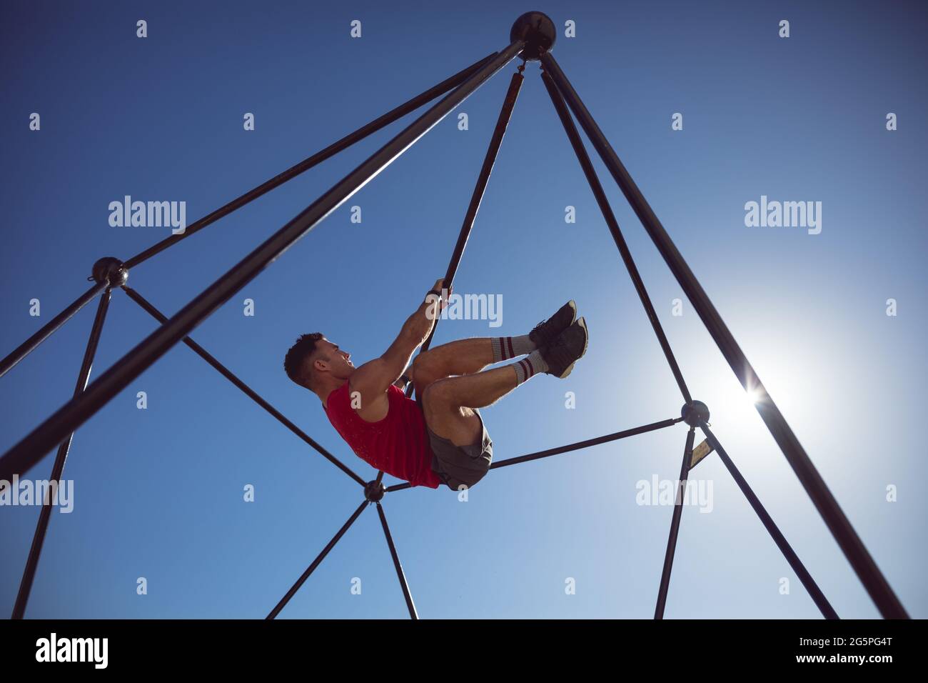 Caucasian muscular man hanging on exercise frame outdoors Stock Photo ...