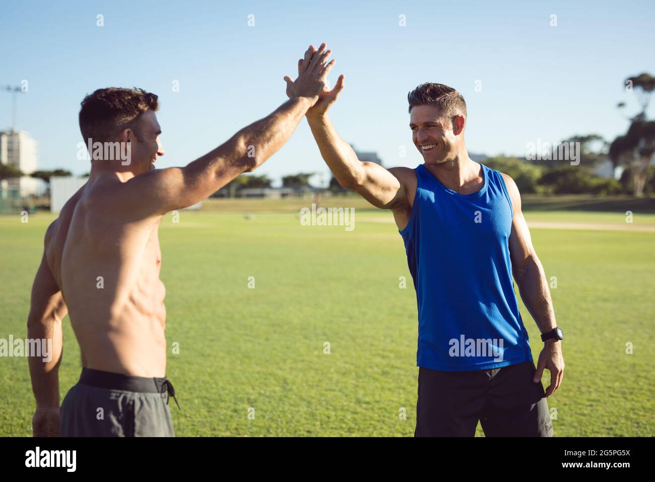Two happy caucasian muscular men exercising outdoors, smiling and high ...