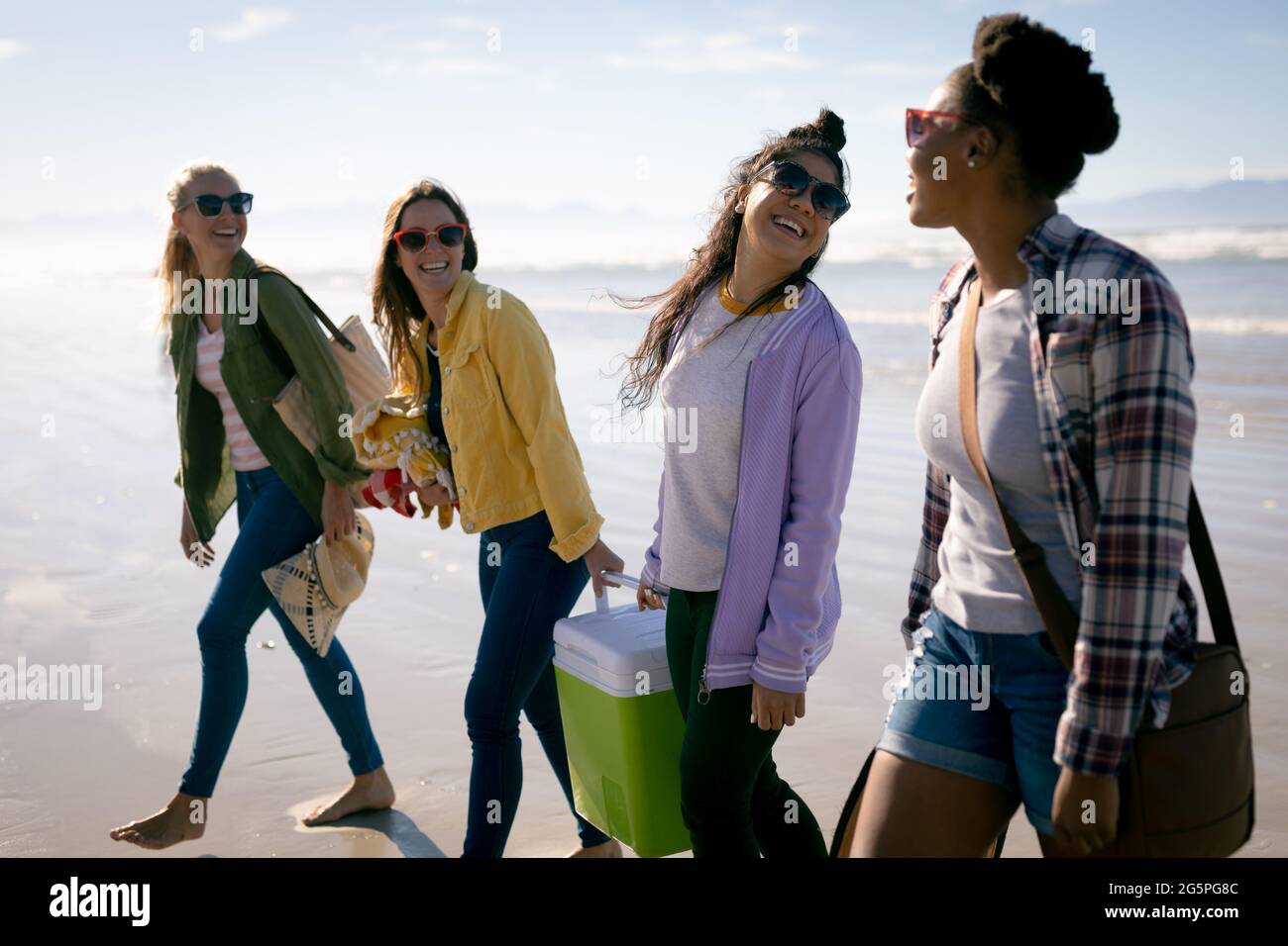 Happy group of diverse female friends having fun, walking along beach and laughing Stock Photo ...