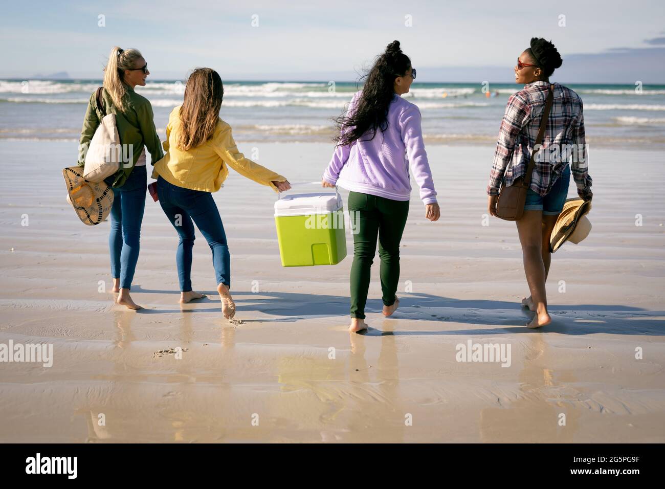 Happy group of diverse female friends having fun, walking along beach laughing Stock Photo - Alamy