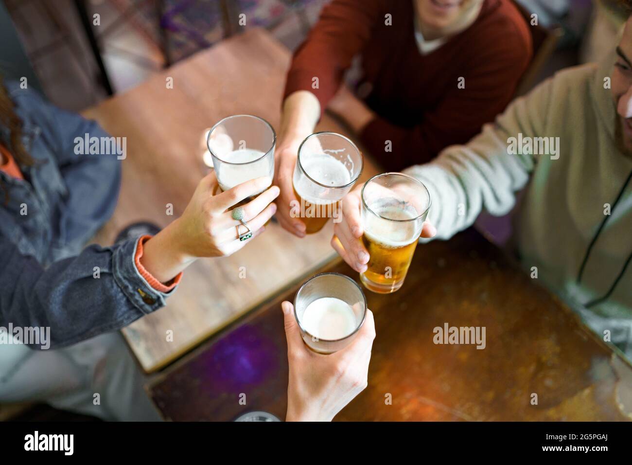 Gathering of best friends sitting in the pub rising beer glasses ...