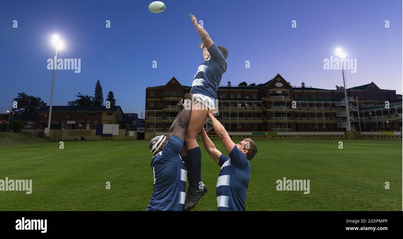 Composition of male rugby team catching ball at sports field Stock ...