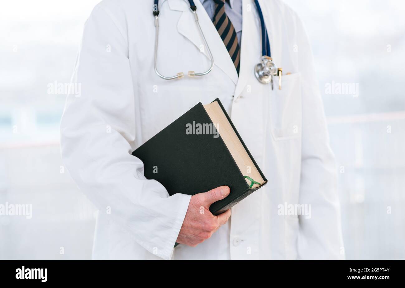 Doctor standing and holding a medical textbook Stock Photo - Alamy