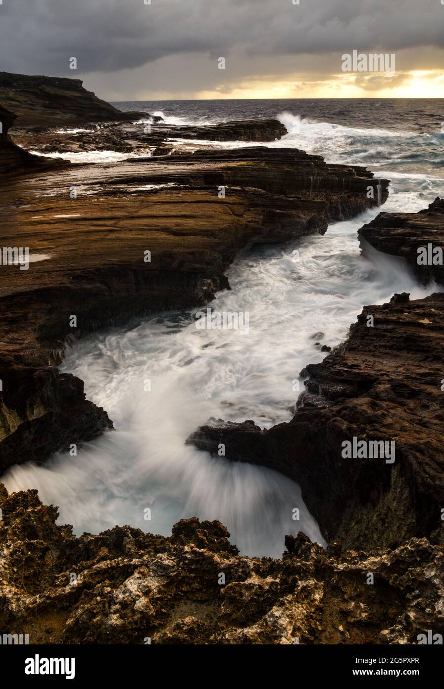 Spectacular sunrise with ocean water crashing and flowing on volcanic ...