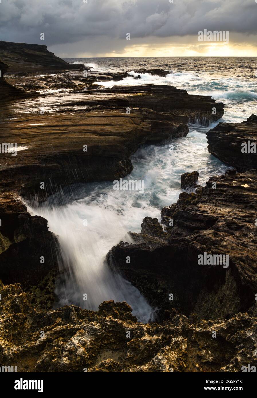 Spectacular sunrise with ocean water crashing and flowing on volcanic ...