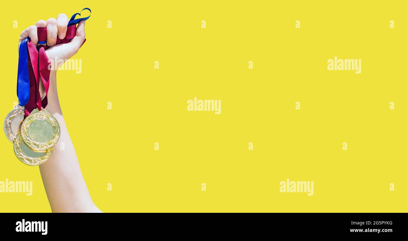 Close up of hand holding multiple medals against yellow background ...