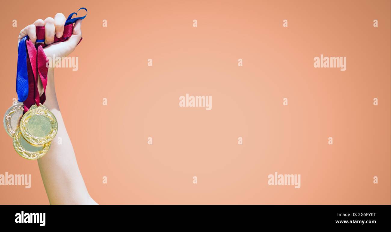 Close up of hand holding multiple medals against orange background ...