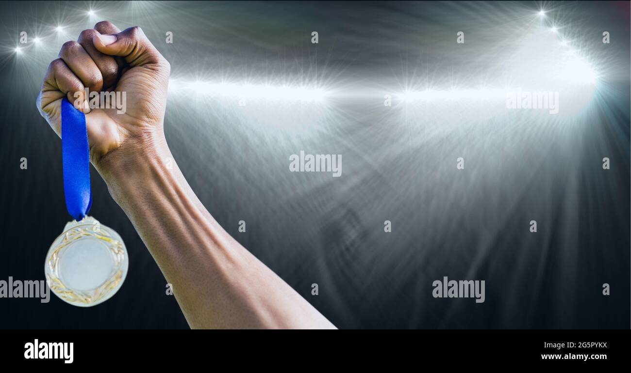 Close up of hand holding multiple medals against flood lights in ...