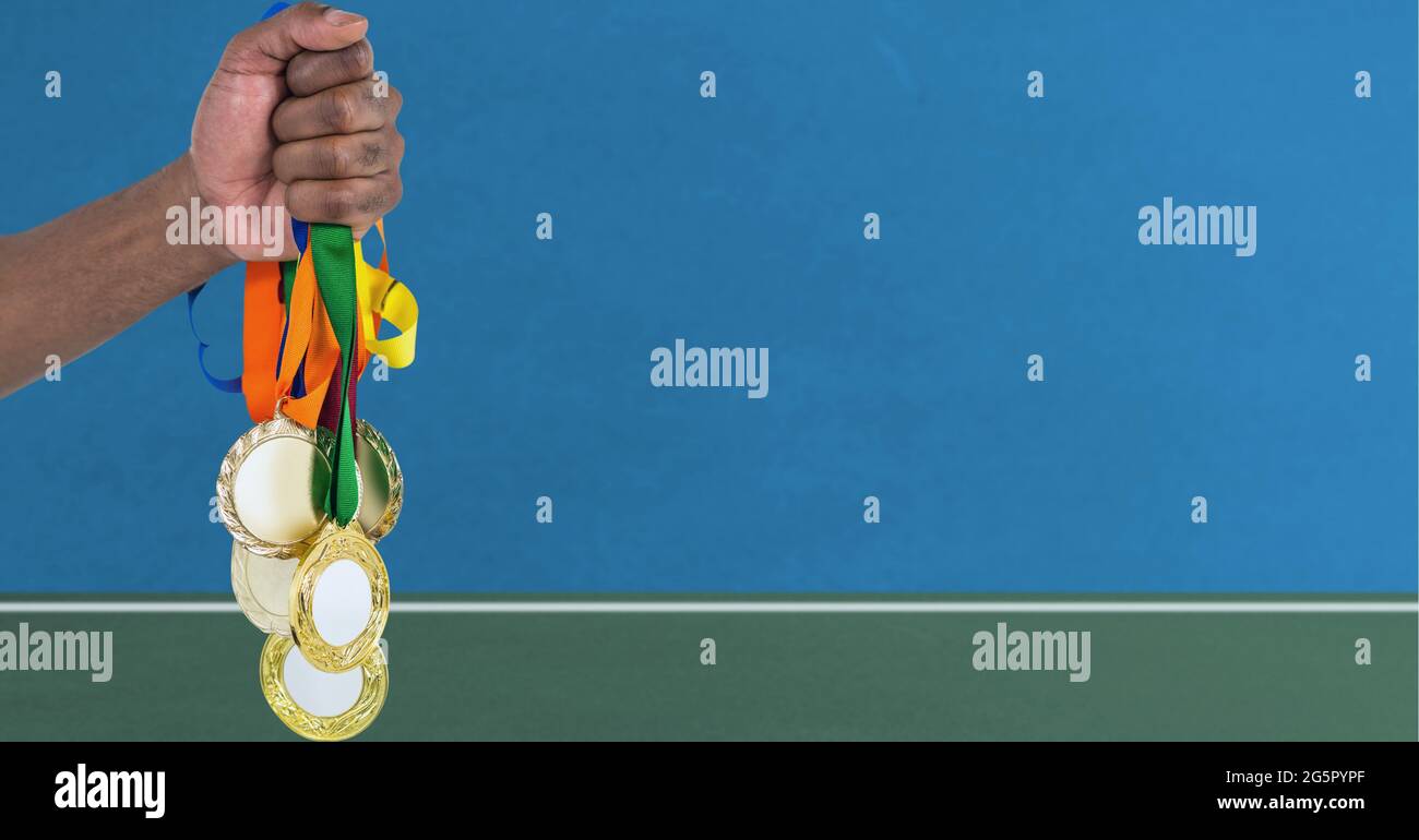 Close up view of hand holding multiple medals against blue and green ...
