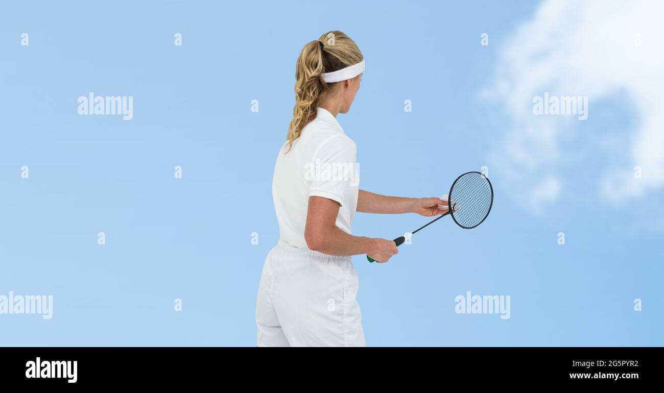 Rear view of female badminton player playing against clouds in blue sky ...