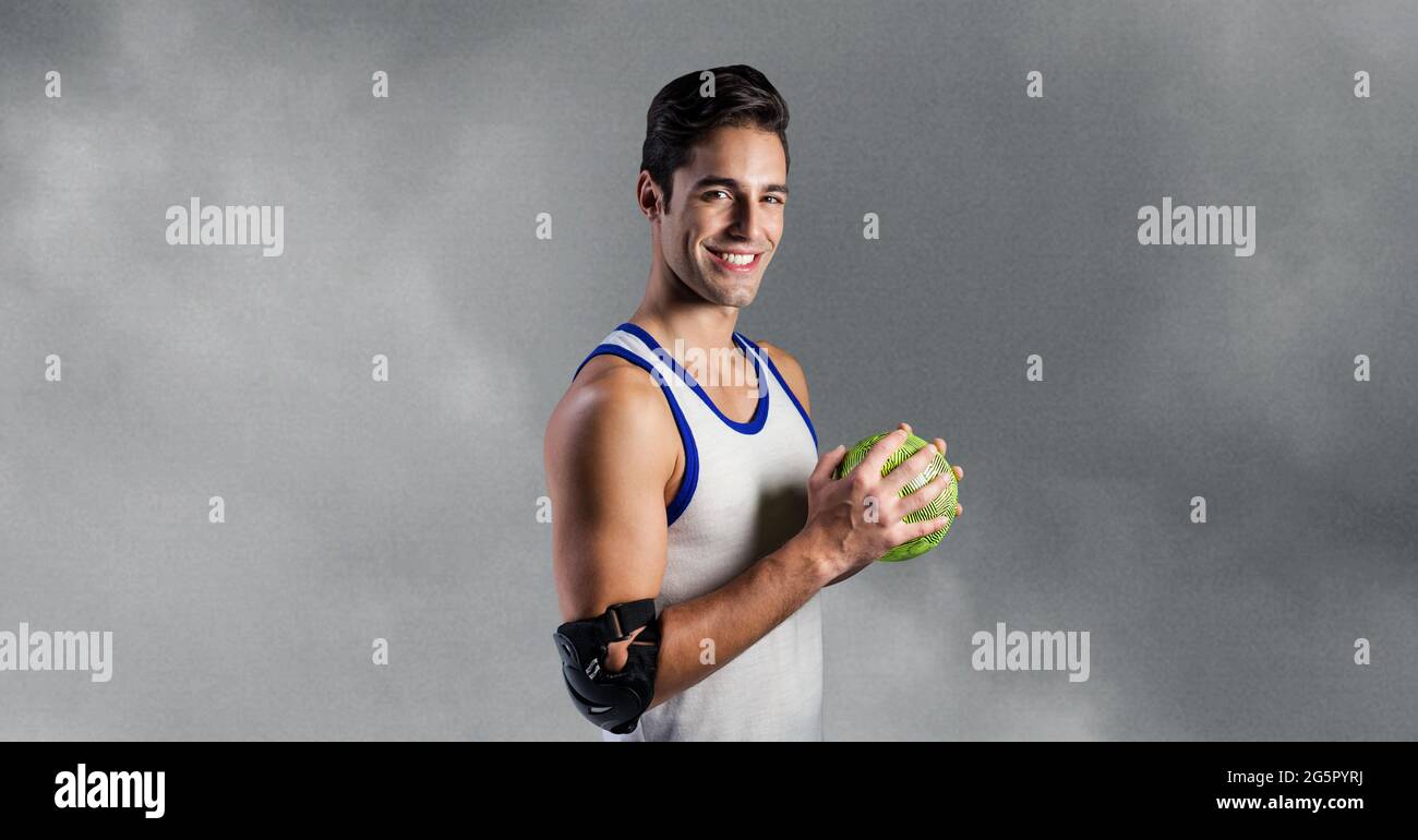 Portrait of caucasian male handball player holding a ball smiling ...