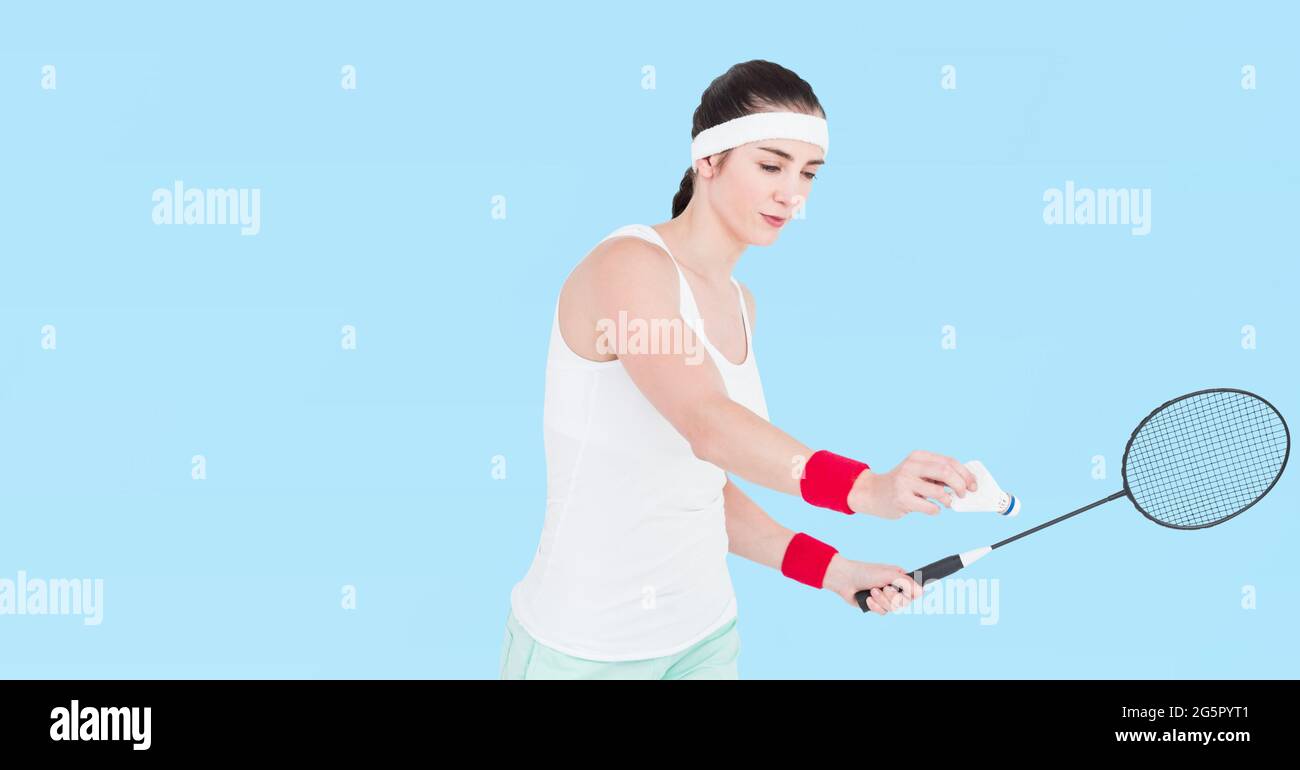Asian female badminton player holding racket against light blue ...