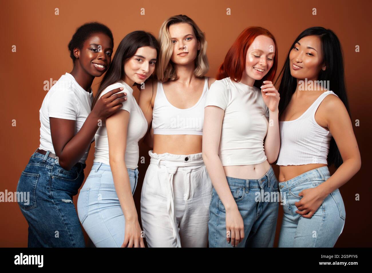young pretty asian, caucasian, afro woman posing cheerful together on brown background ...