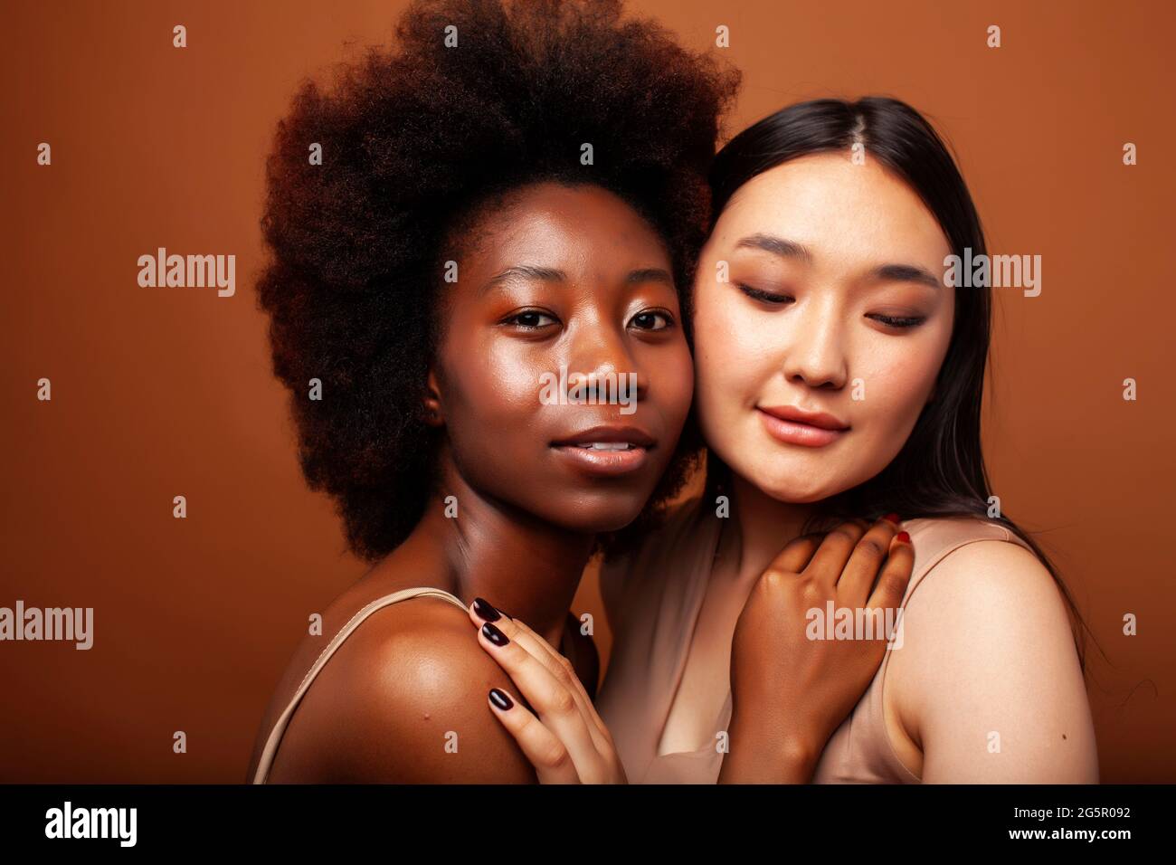 young pretty asian, afro woman posing cheerful together on brown ...