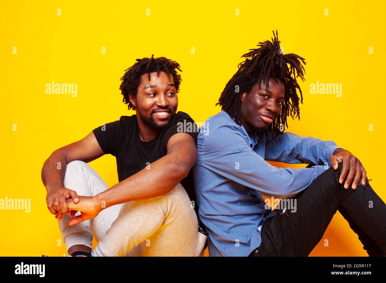two african american guys posing cheerful together on yellow background ...