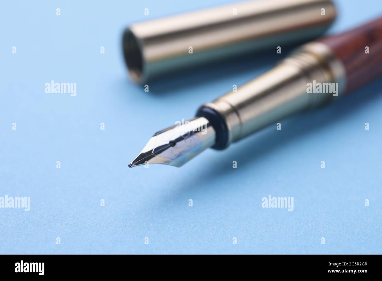 Open fountain pen on light blue background Stock Photo - Alamy