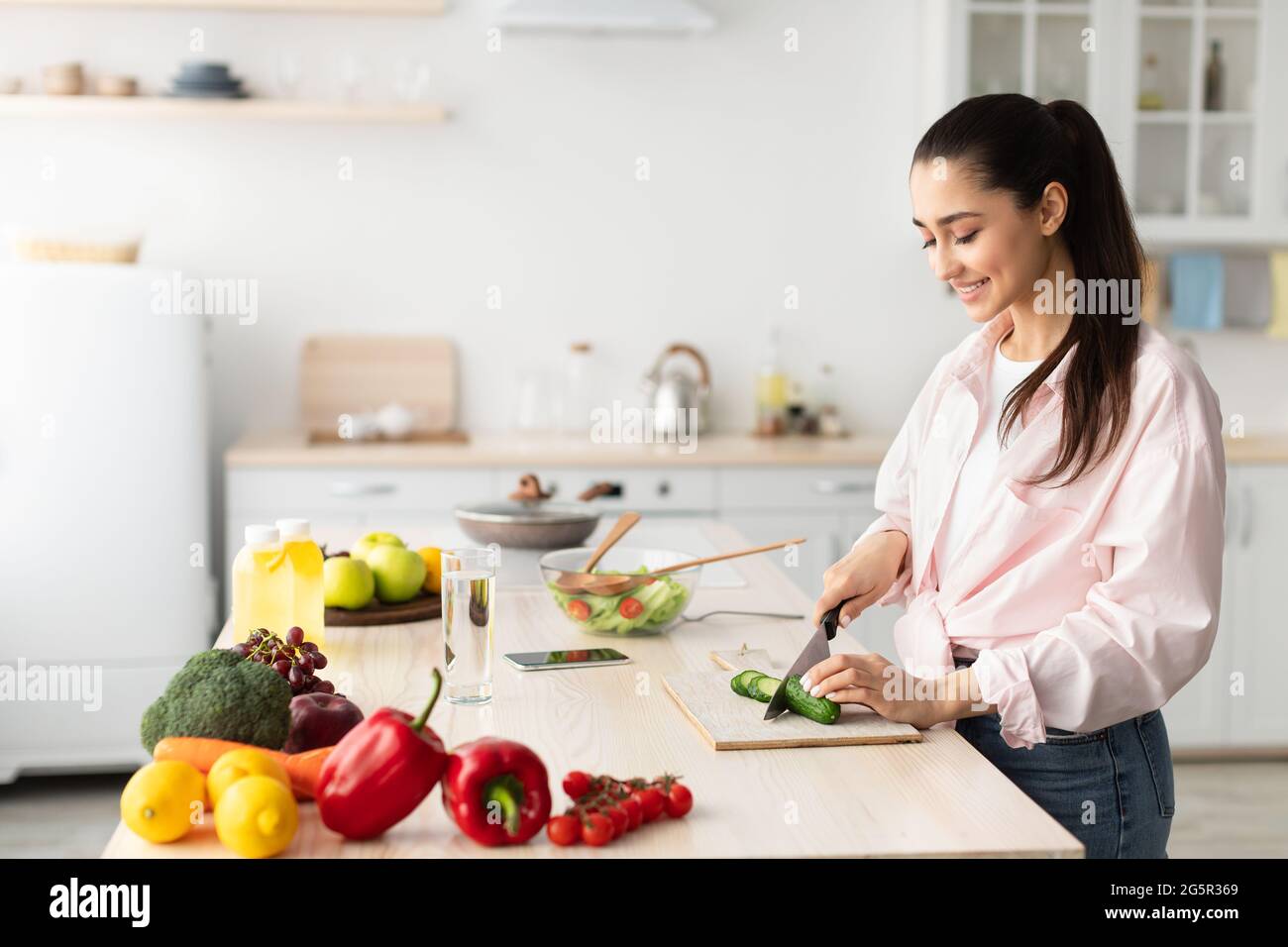 Portrait of smiling young lady cooking fresh salad Stock Photo - Alamy