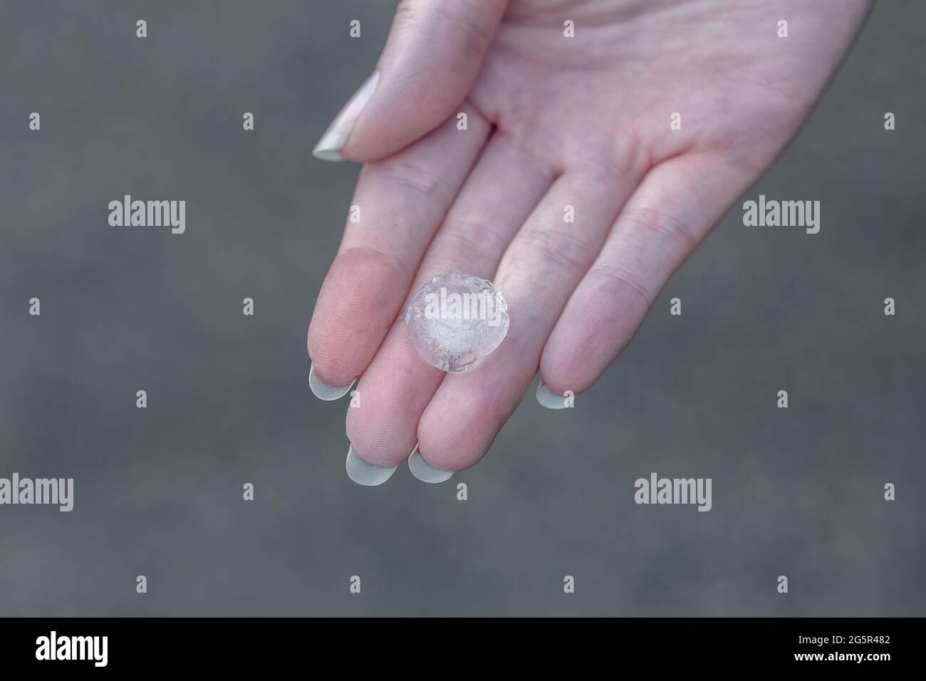 Female hand holds hailstone. Summer hail in the hand of a woman. Large ...