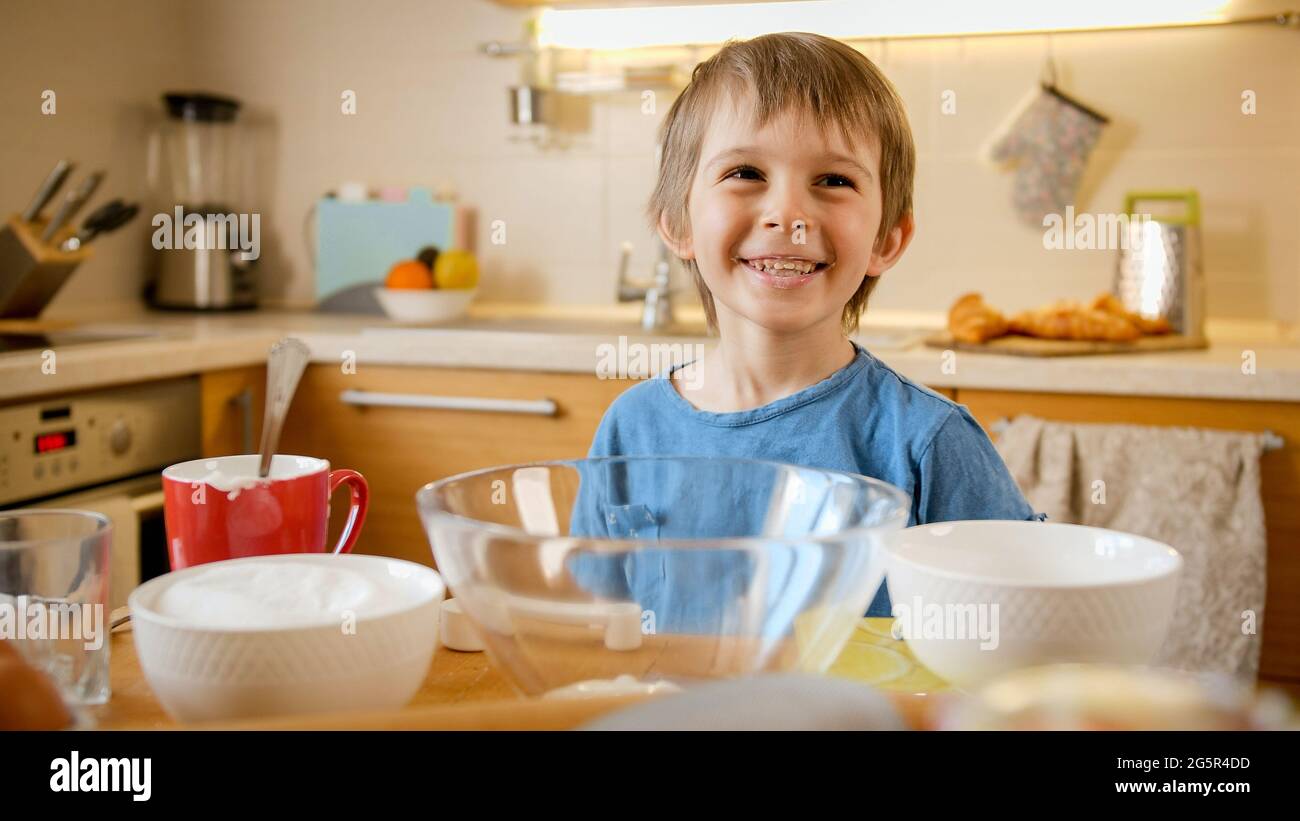 Funny laughing little boy eating creme for baking pie with spoon ...