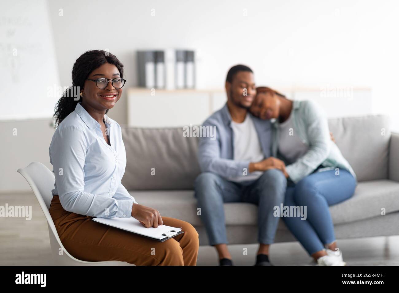Cheerful female psychologist and young black couple hugging after ...