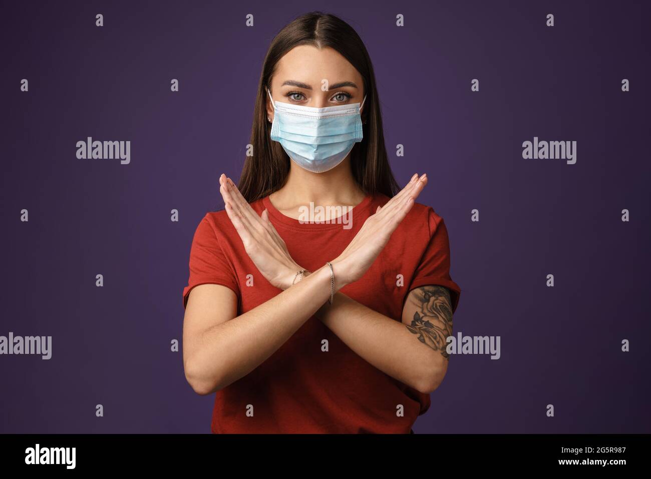 Beautiful brunette girl in protective mask showing stop gesture ...