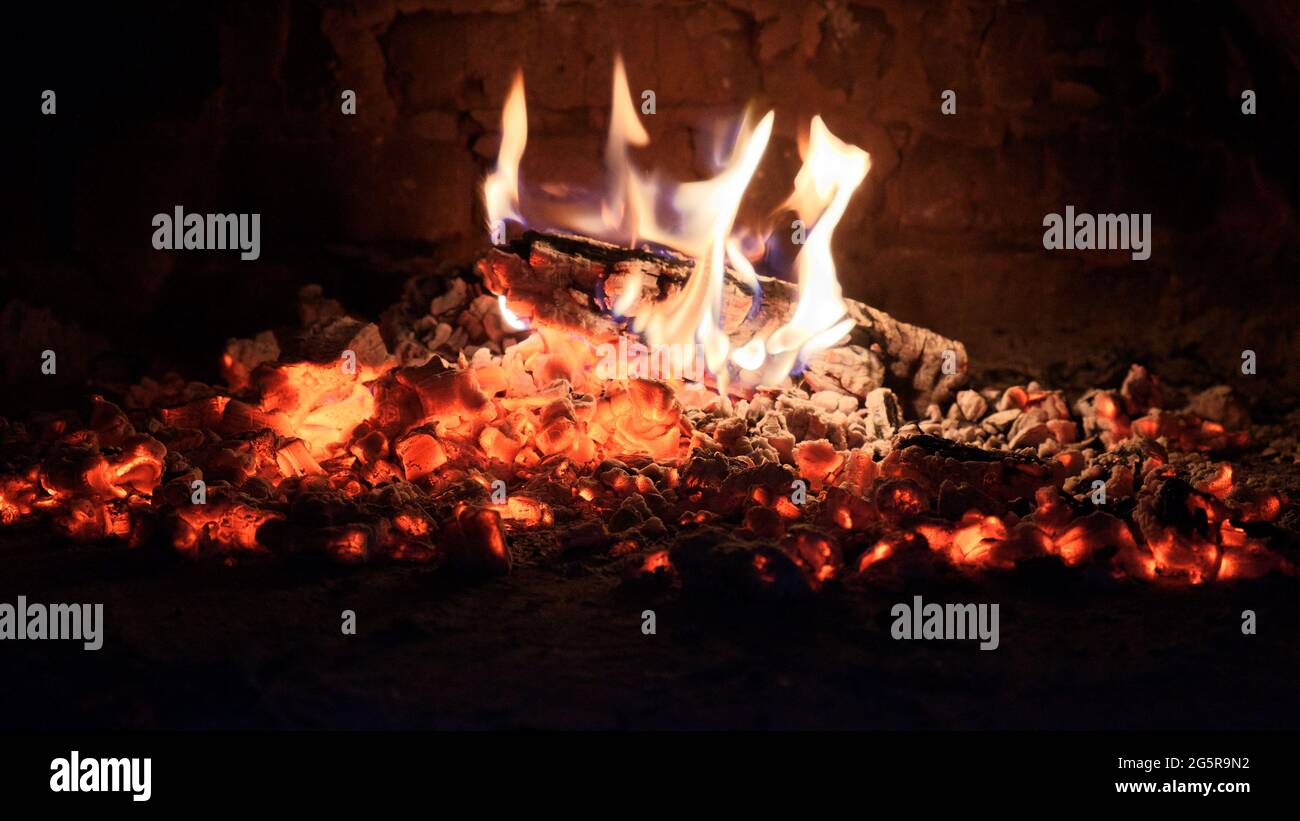 Logs of firewood burn out in the oven. Coals and flames in the ...