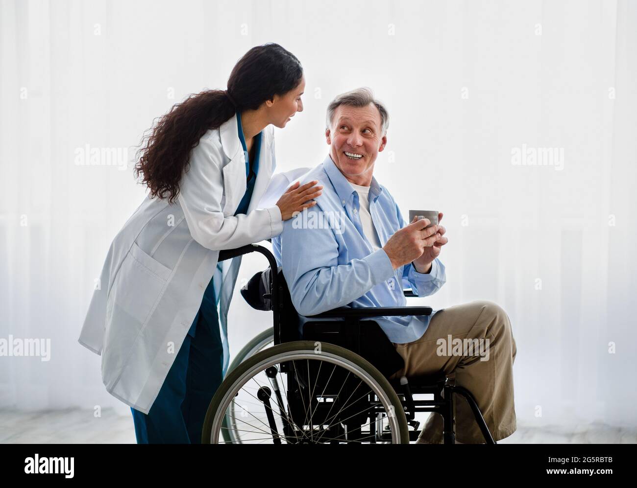 Young female doctor helping senior handicapped man in wheelchair ...