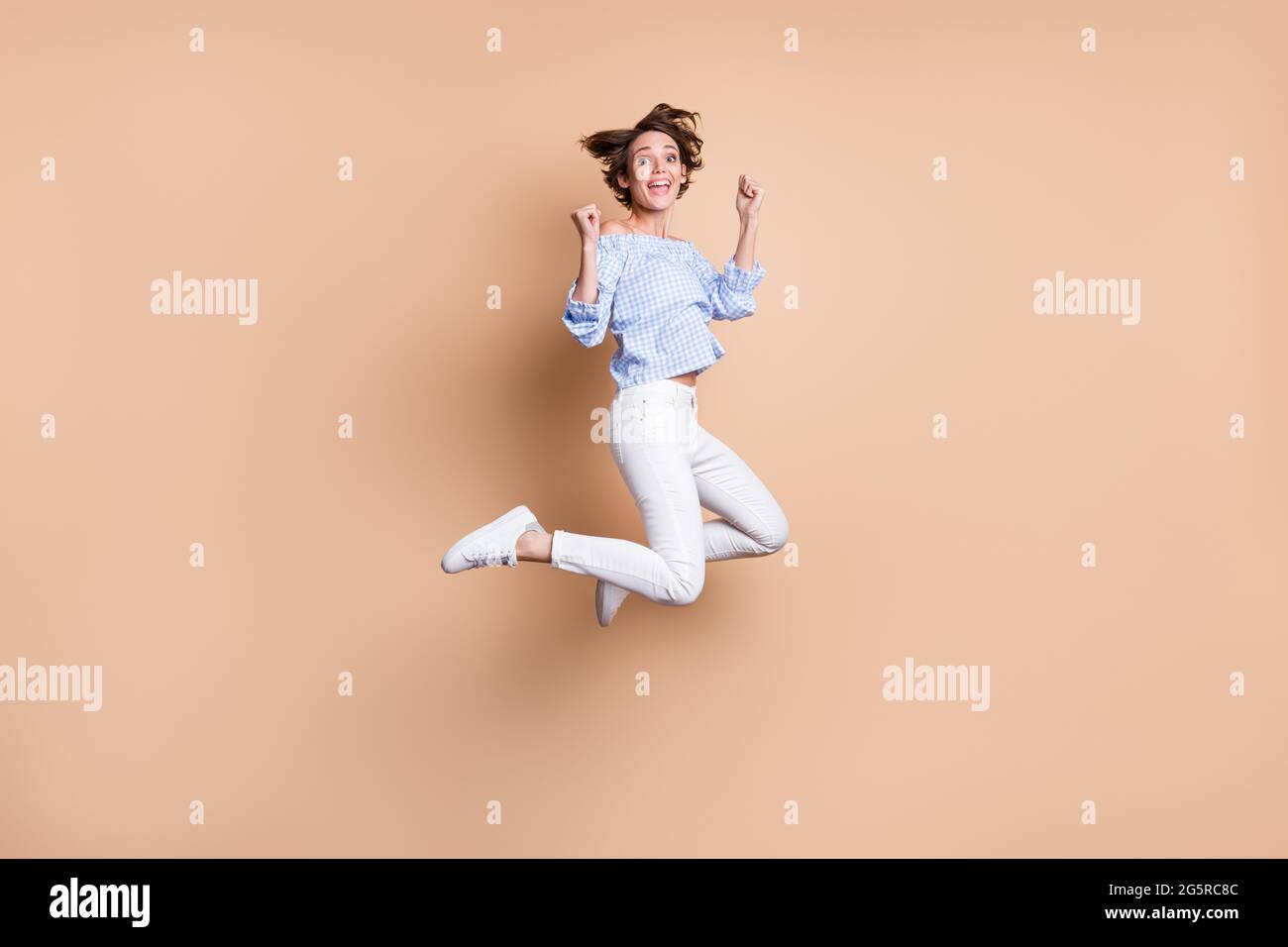 Full size photo of happy victorious young woman jump up air raise fists ...